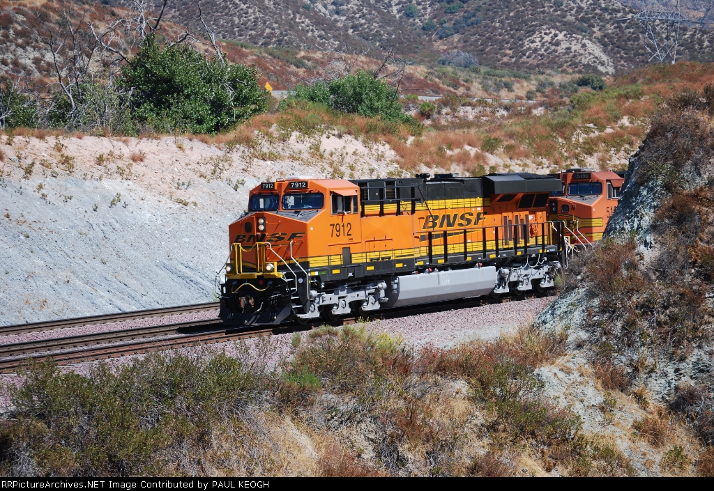 BNSF 7912 and BNSF 5190 poke their noses from aound the curve as they continiue south/west with ...